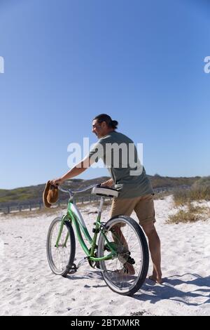 Senior Caucasian man carrying a bike at the beach Stock Photo - Alamy