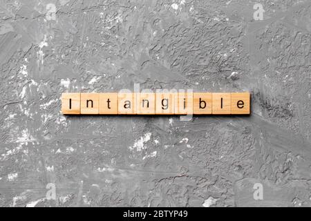 intangible word written on wood block. intangible text on wooden table ...