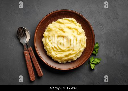 Mashed potatoes, boiled puree in a brown plate on a black slate ...