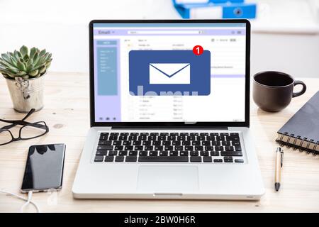 E-mail @ at symbol on an office desk with man on laptop computer Stock ...