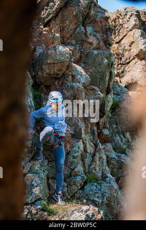 Man climbing a rock short before reaching the summit Stock Photo - Alamy