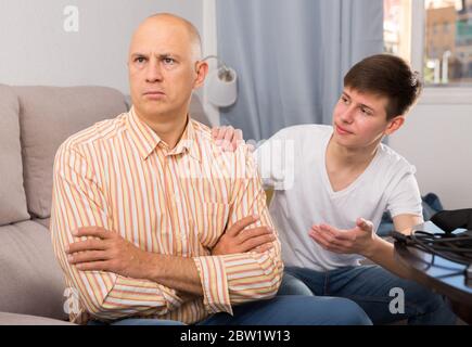 Teen boy trying to apologize his irritated father after dispute Stock ...