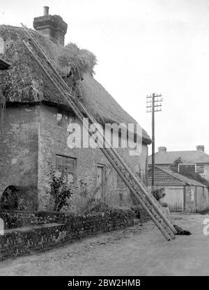 The craft of thatching - The thatcher at work on a picturesque Cottage ...
