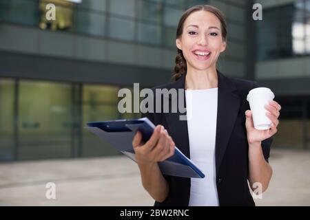 Female director is examining documents and drinking coffee near office ...