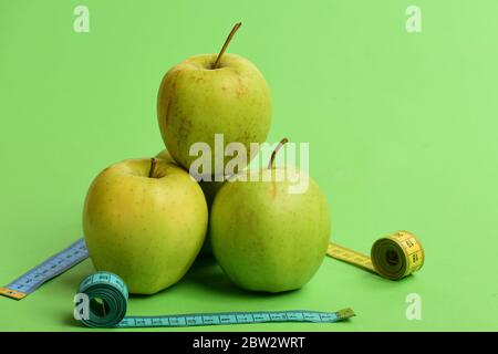 Apples near measuring tape rolls on green background, top view Stock ...
