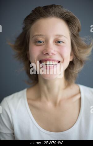 Nice smiling joyfully female model with fair hair looking at camera ...