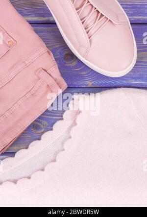 Womanly pink leather shoes, sweater, shawl and pants lying on old blue ...