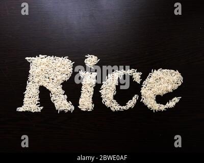 Writing the word Rice with rice seeds on a table with brown wooden ...