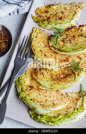 Roasted cabbage steaks on plate over white background. Top view, flat ...