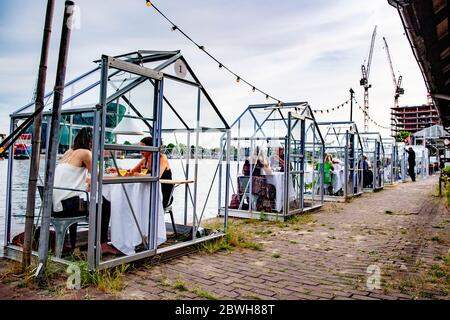 Customers sit in small glasshouses as they enjoy their dinner while ...