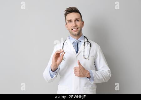 Male doctor with flashlight on grey background Stock Photo - Alamy