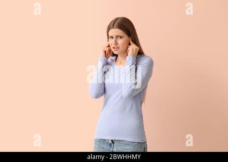 Young woman suffering from loud noise on grey background, back view ...
