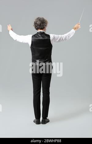 Back view of a male band conductor in formal suit conducting his ...