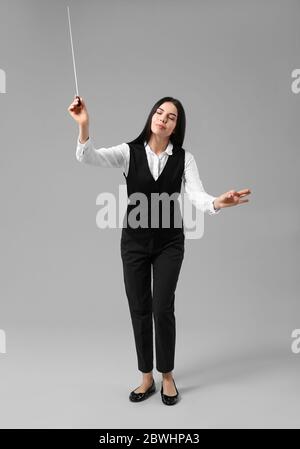 Young female conductor on grey background Stock Photo - Alamy