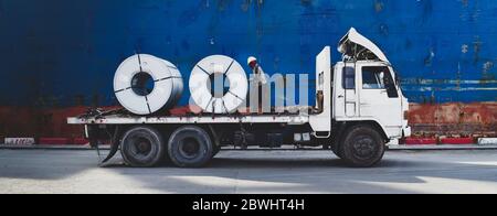 Truck load steel coils alongside big ship. Steel cargo discharged from ...