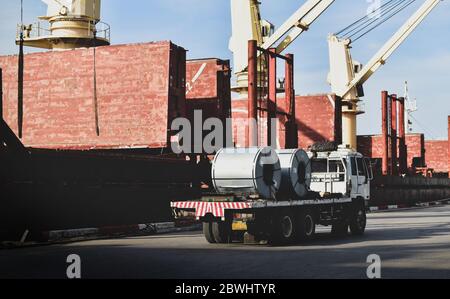 Truck load steel coils alongside big ship. Steel cargo discharged from ...