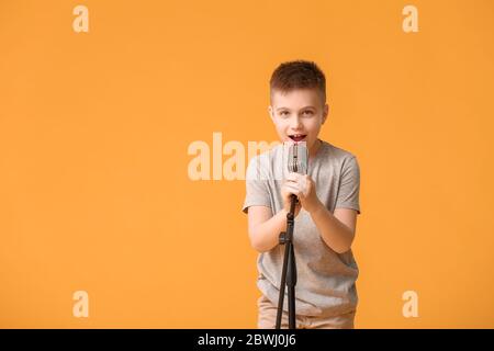 Cute little boy singing against color background Stock Photo - Alamy