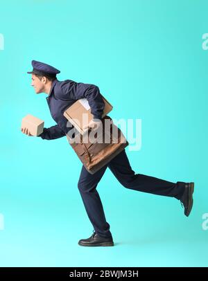 Handsome running postman on color background Stock Photo - Alamy