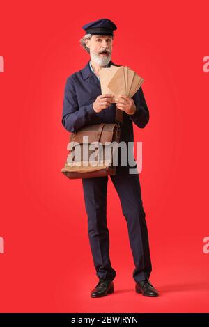 Surprised old postman on color background Stock Photo - Alamy