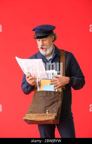 Surprised old postman on color background Stock Photo - Alamy