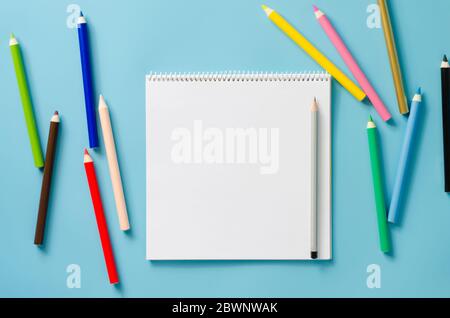 Blank notebook and set of colorful pencils on blue background. Paper ...