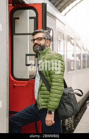 Portrait of man getting into a train Stock Photo - Alamy
