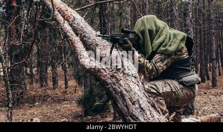 Photo of a fully equipped camouflaged forest sniper with rifle standing ...
