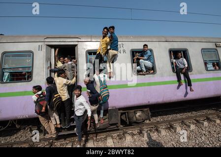 Commuters hang out of an overcrowded Indian Railways train, at Noli ...