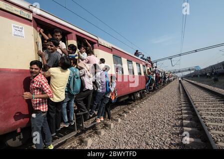 Commuters hang out of an overcrowded Indian Railways train, at Noli ...