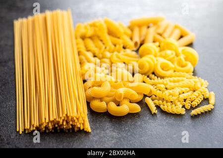Variety of raw pasta types, farfalle bow-tie, fettuccine or tagliatelle ...