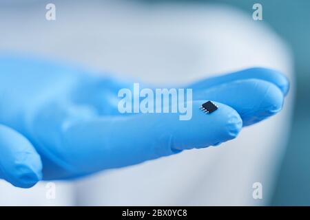 Hand holds chip compenent. Embedding the chip under human skin ...