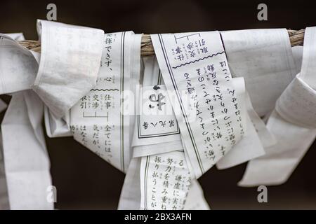 Omikuji (fortune-telling paper strip) tied to a rope at a Japanese temple in Nikko, Japan Stock ...
