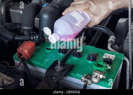 Hands of technician adding water to battery in a service center Stock ...