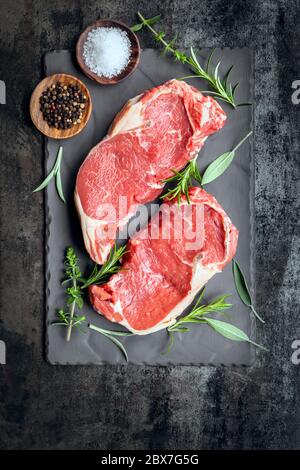 Raw beef steaks, with herbs, on wooden table. Concept of food cooking ...