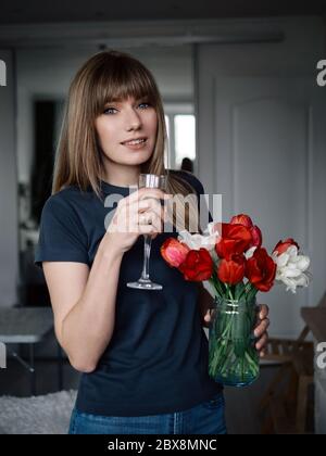 Smiling blonde girl enjoying champagne in subdued color lighting of ...