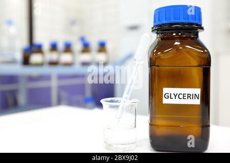 Glycerin in glass beaker and brown amber bottle inside laboratory with ...