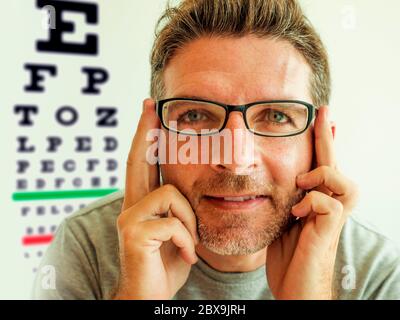 Attractive man checking vision trying glasses at optometrist . Cheerful ...