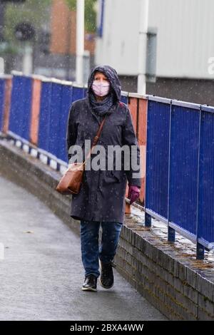 A woman walks through the streets of Sheffield during a heavy rainfall ...