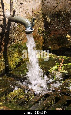 Water from an underground burst pipe escapes through the road surface ...
