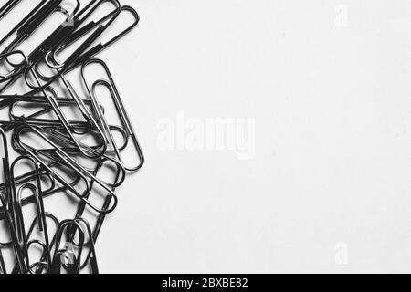 Lots of paperclips spilled on the left side of the image on a white ...