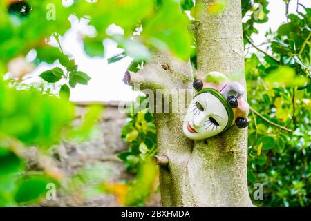 human face baked clay mask on a tree in a garden UK Stock Photo - Alamy