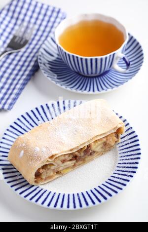 Slice of strudel under powdered sugar and a cup of tea Stock Photo - Alamy