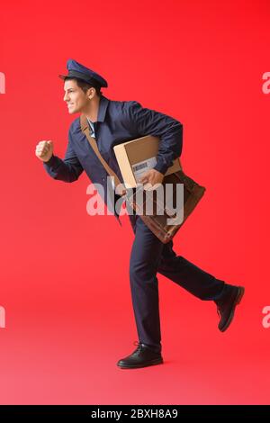 Handsome running postman on color background Stock Photo - Alamy