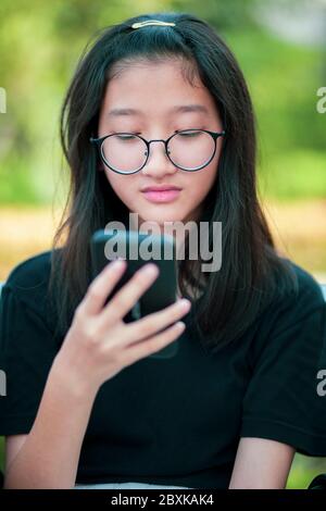 asian teenager reading message in smart phone Stock Photo - Alamy