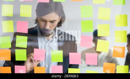 Businessman is thinking about he new ideas while writing them down in ...