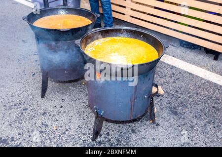 Very large cauldron cooking food during campfire, big pots on fire ...