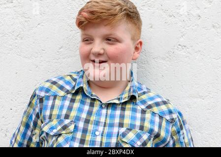 Plump red-haired boy is smiling. A boy in a plaid shirt stands on a ...