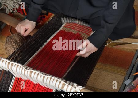 An Arab woman makes a traditional sadu weaving. Hands of a weaver close ...