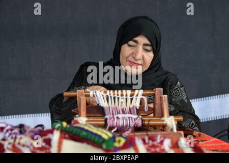 A senior arabian woman makes a traditional sadu weaving. Hands of a ...