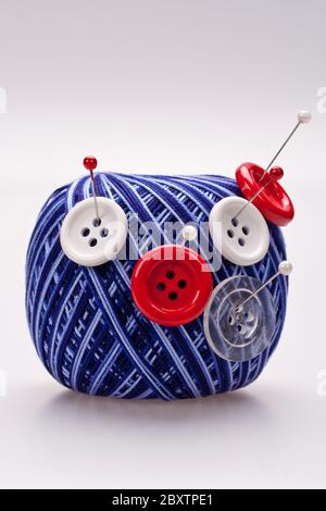 pins in wool ball with buttons Stock Photo - Alamy